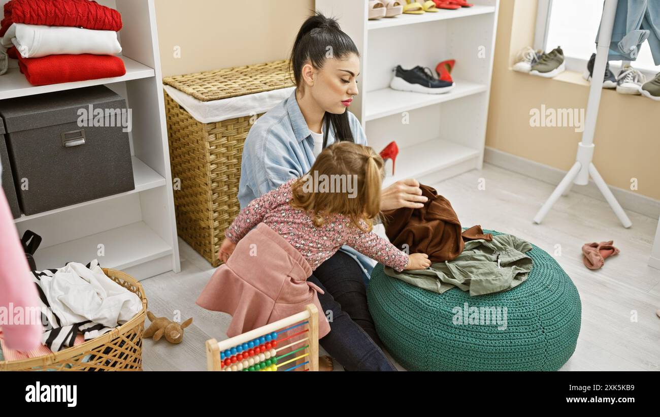 A loving mother and daughter tidying up clothes in a neat, well ...