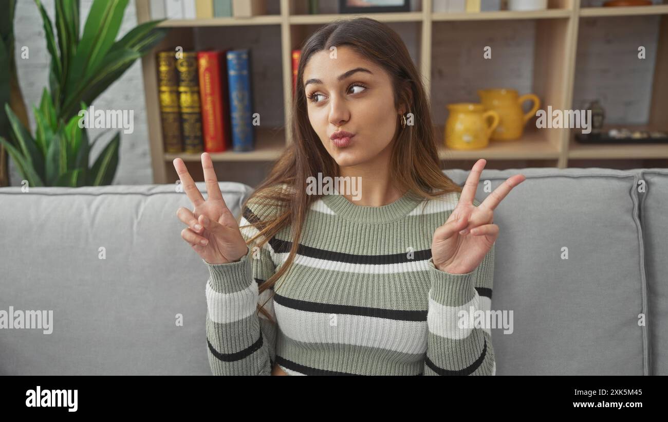 A young hispanic woman poses playfully on a sofa indoors, flashing a ...