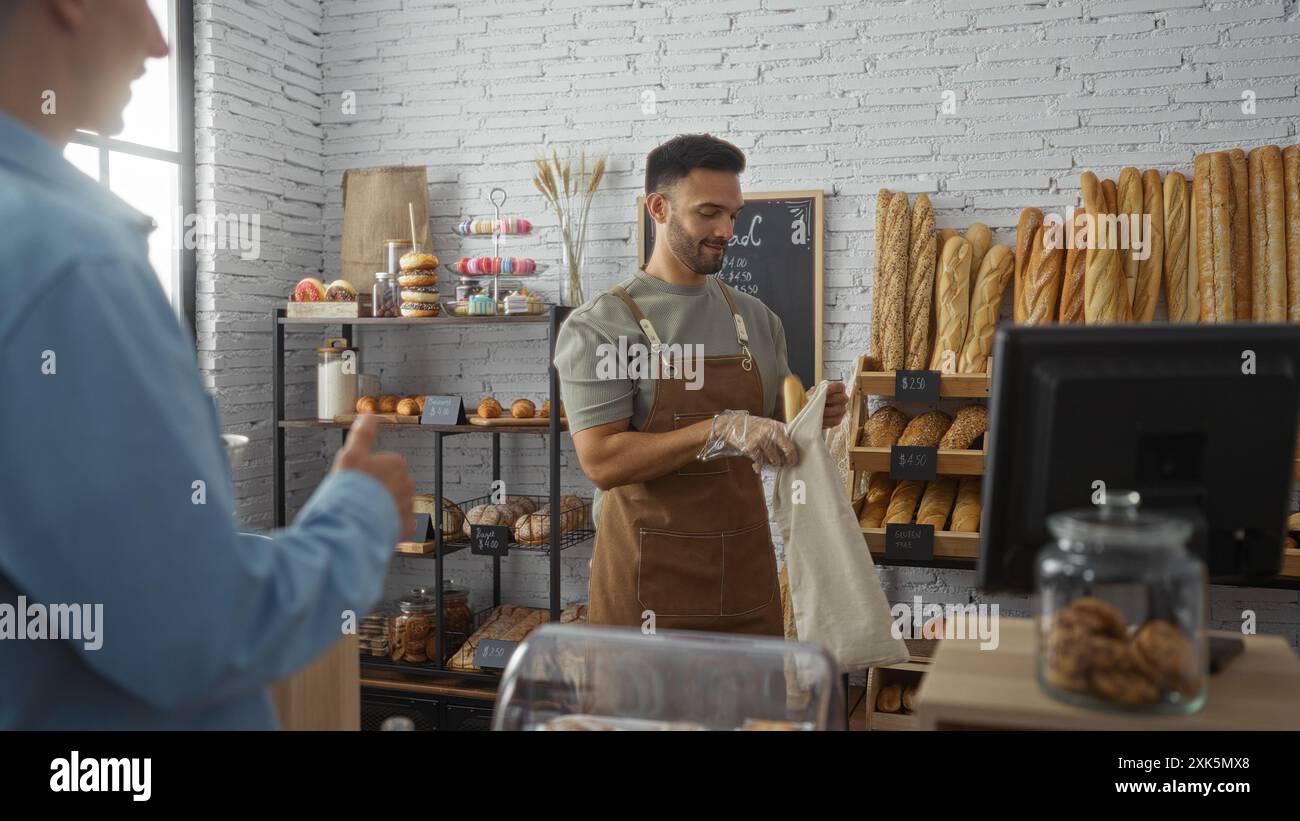 Two men in a bakery with one man wearing an apron and glove bagging ...