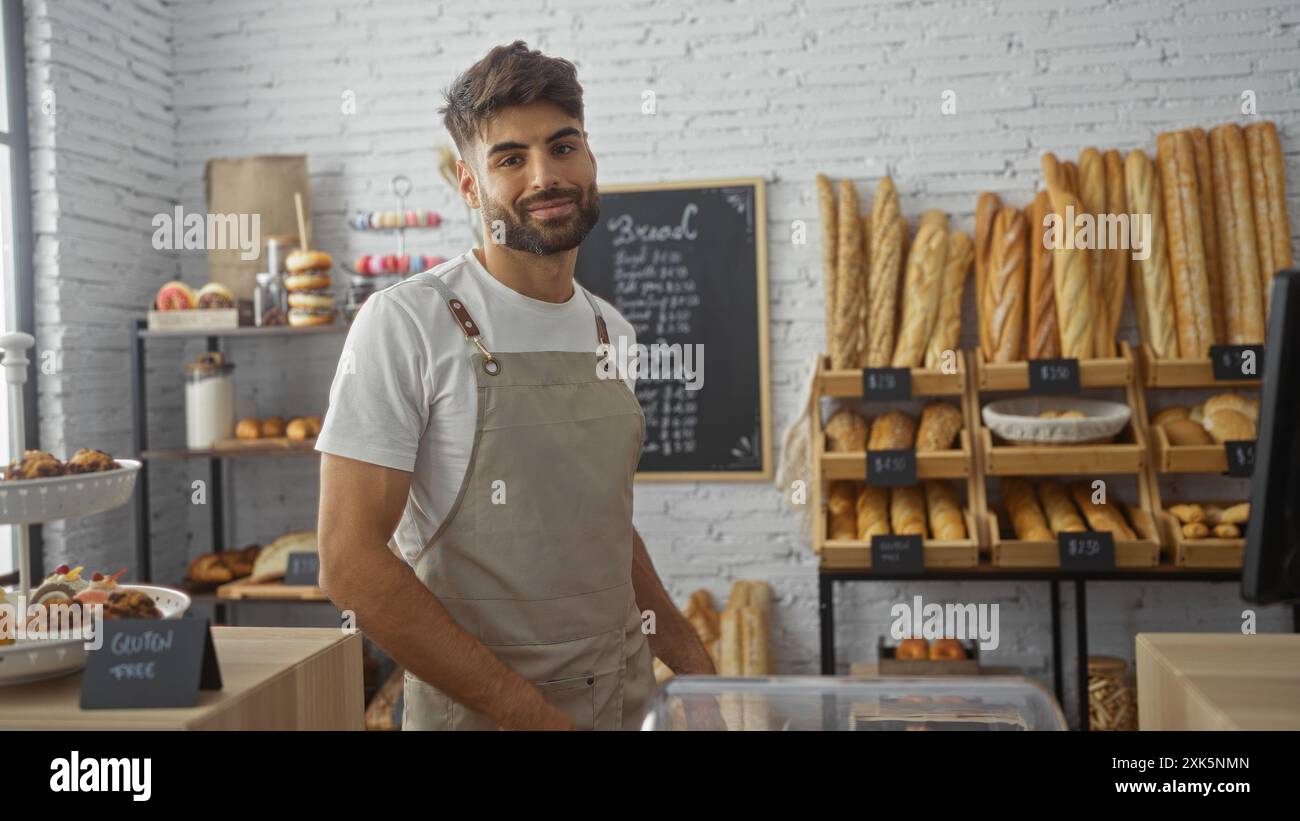Young man with beard standing in a bakery shop with various baked goods ...