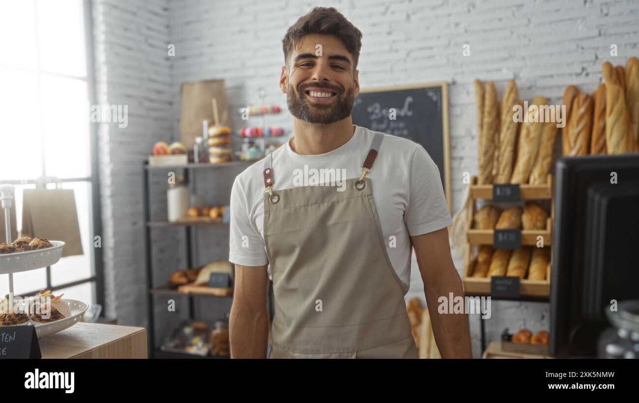Handsome young hispanic man with a beard, smiling inside a bakery with ...