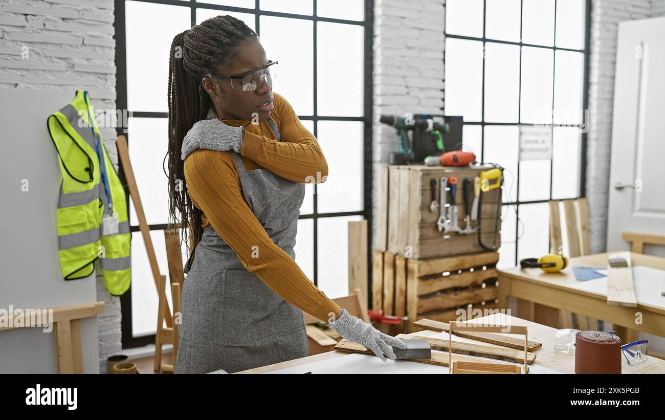 A black woman with braids experiencing back pain in a carpentry ...