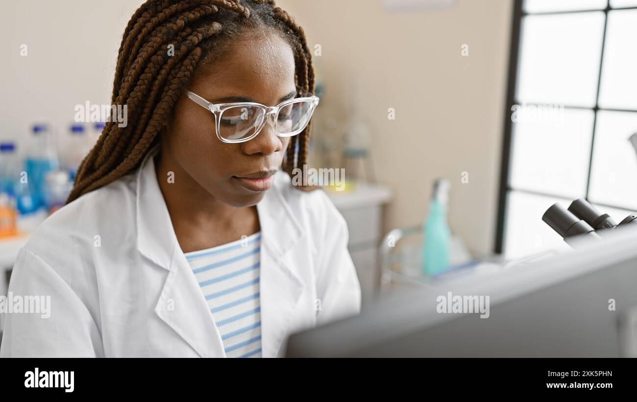 Concentrated african american woman with braids working in a science ...