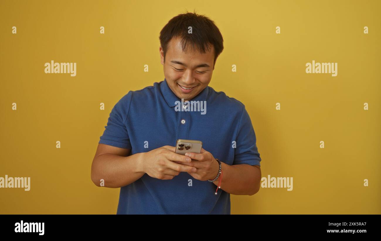 Young chinese man smiling while using a smartphone against a bright ...