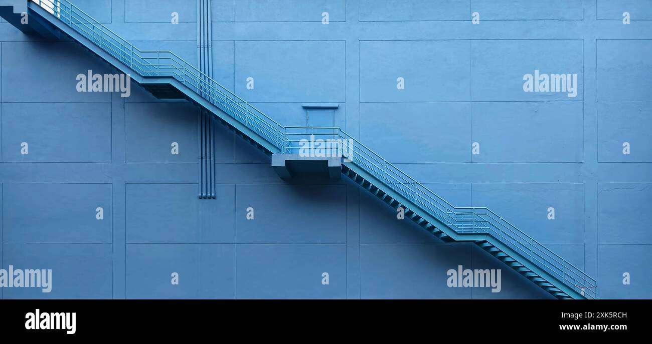 A set of stairs ascending a large blue wall Stock Photo - Alamy