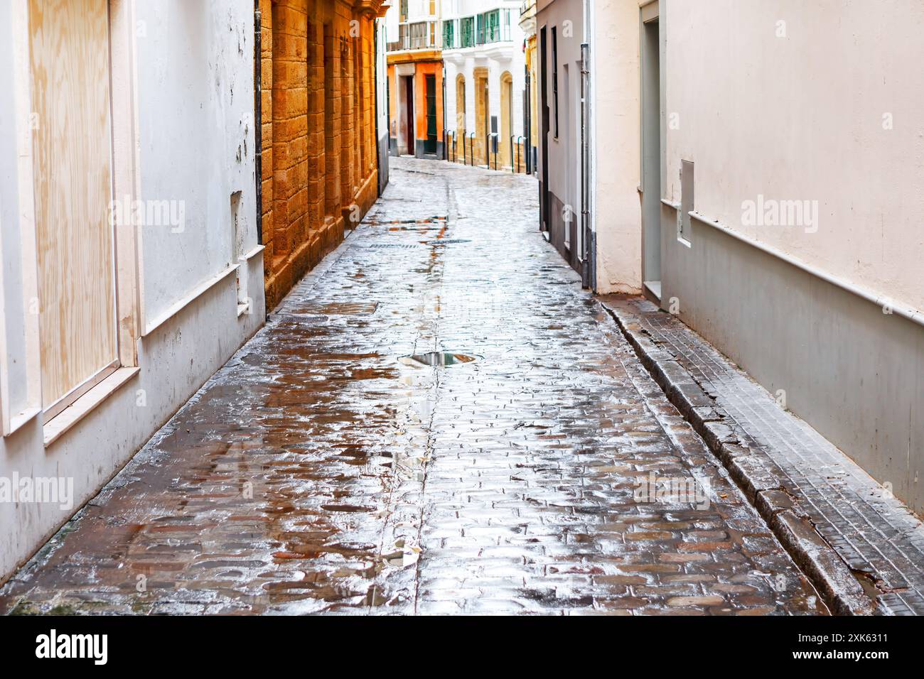 Narrow alleyway with a brick walkway after the rain. The alleyway is ...