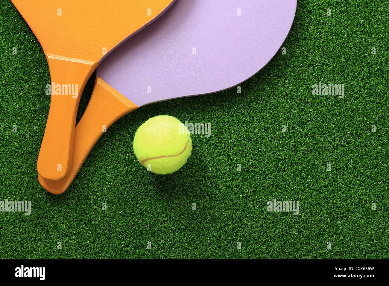 Wooden racket and green ball on the grass, top view. Products for ...
