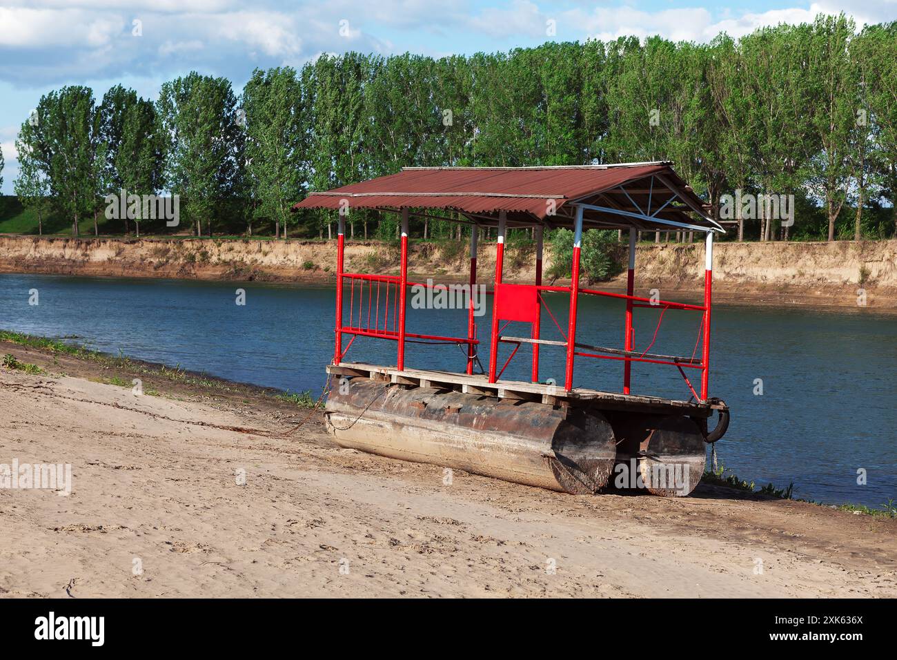Small boat parked on riverside. Red boat with roof sits on the beach ...
