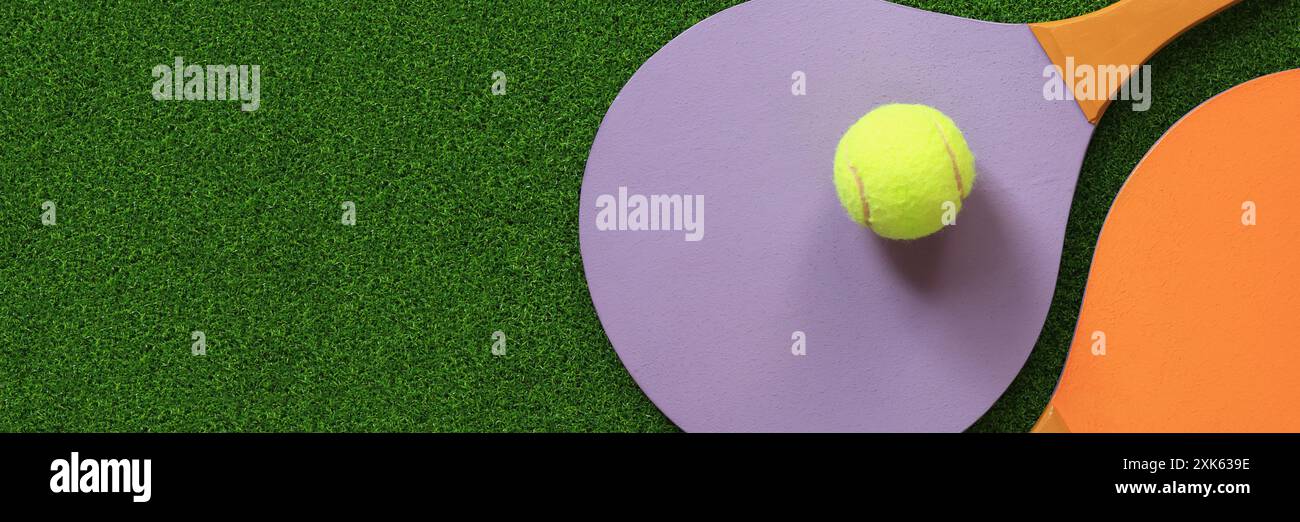 Wooden racket and green ball on the grass, top view. Products for ...