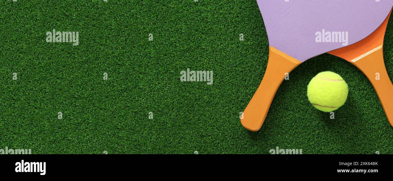 Wooden racket and green ball on the grass, top view. Products for ...
