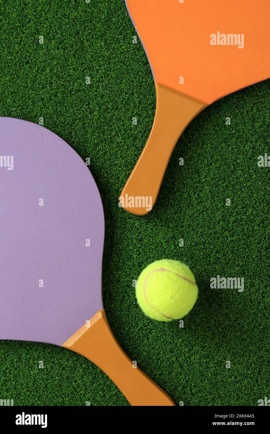 Wooden racket and green ball on the grass, top view. Products for ...