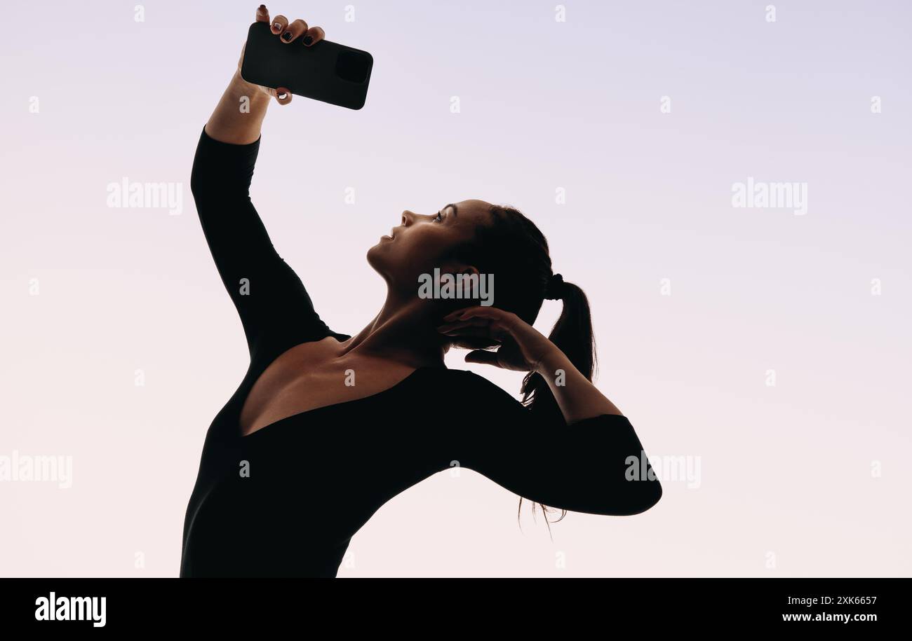 Woman holding her smartphone in a studio, fully immersed in the digital ...