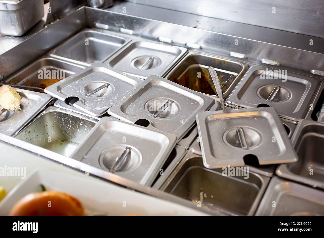 A view of food pan station in a messy fashion, in a restaurant kitchen ...