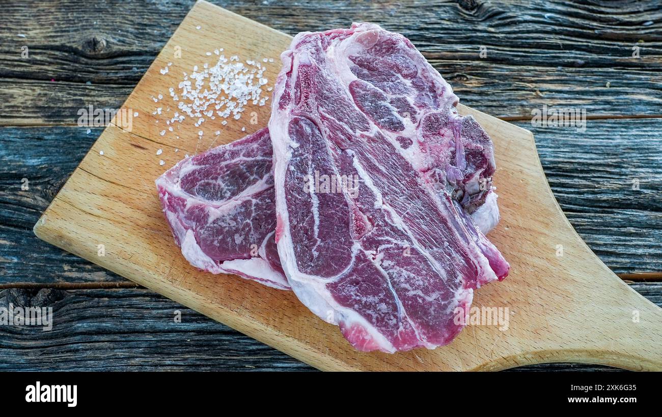 Raw lamb shoulder chops ready for cooking on a wooden cutting board ...