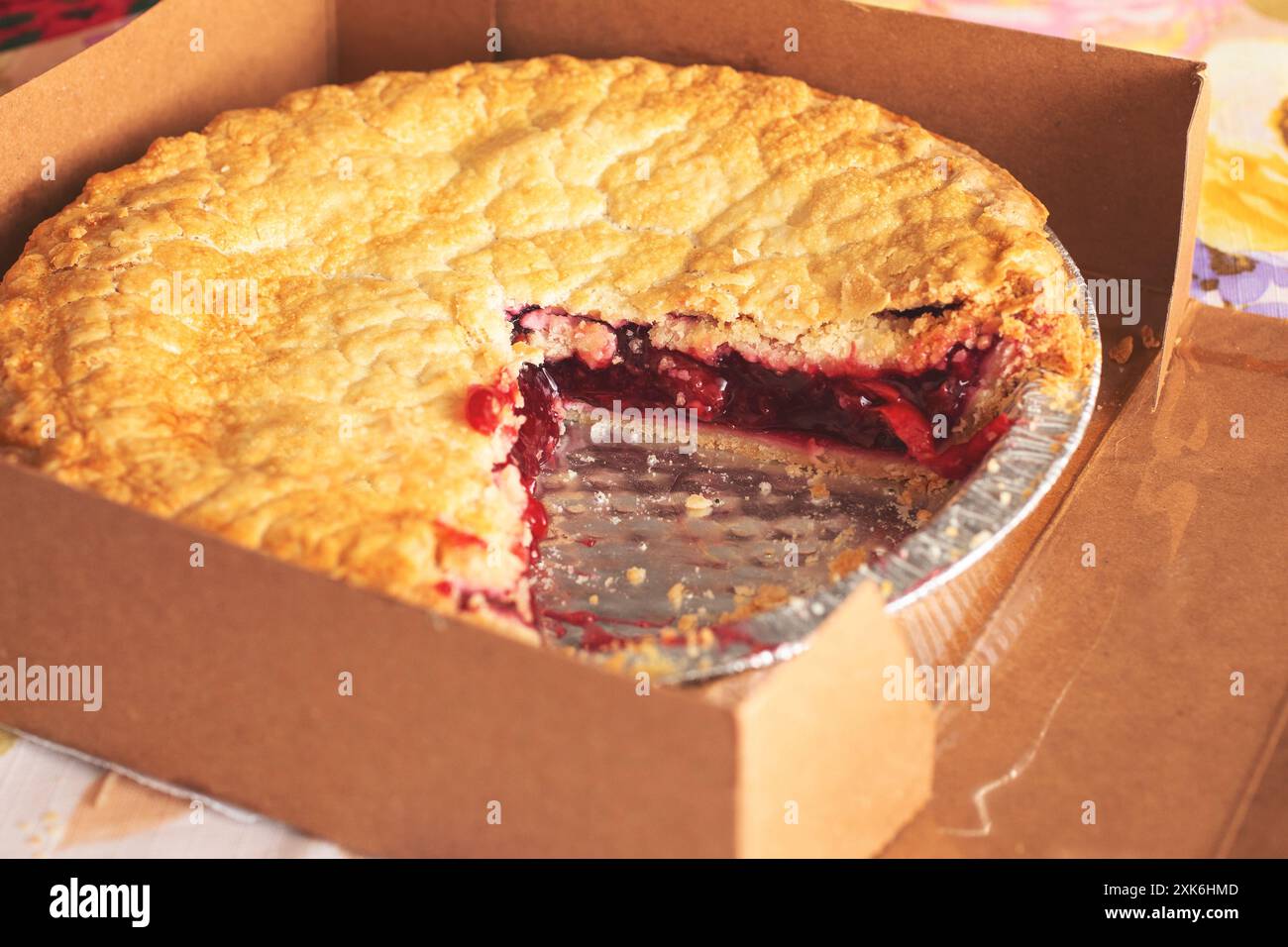 A view of a cherry pie inside a box, featuring a missing piece Stock Photo - Alamy