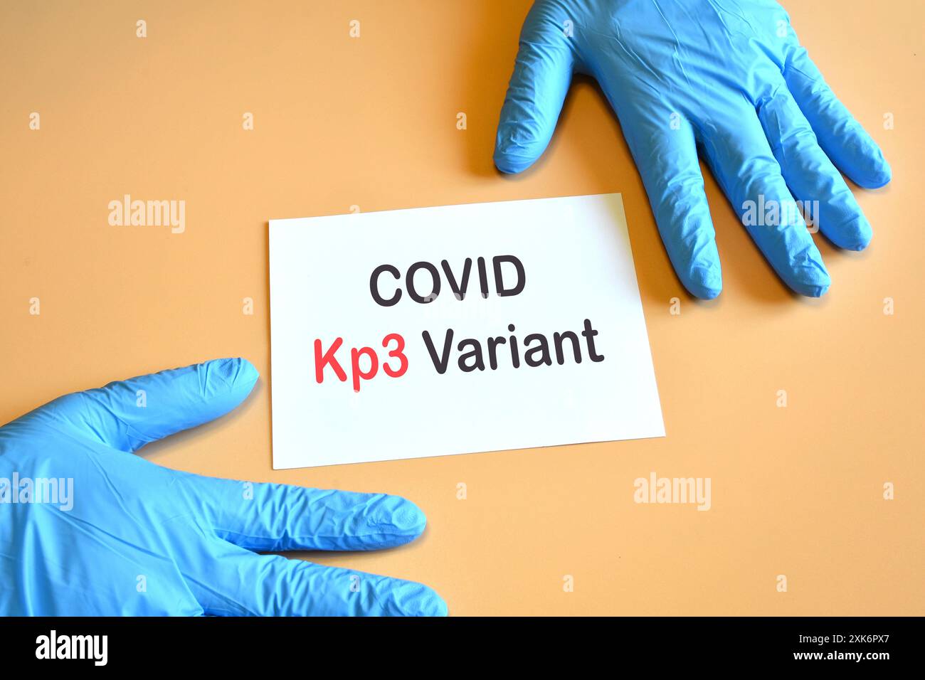 The hands of doctor in blue gloves with white paper and text "Covid Kp3 ...