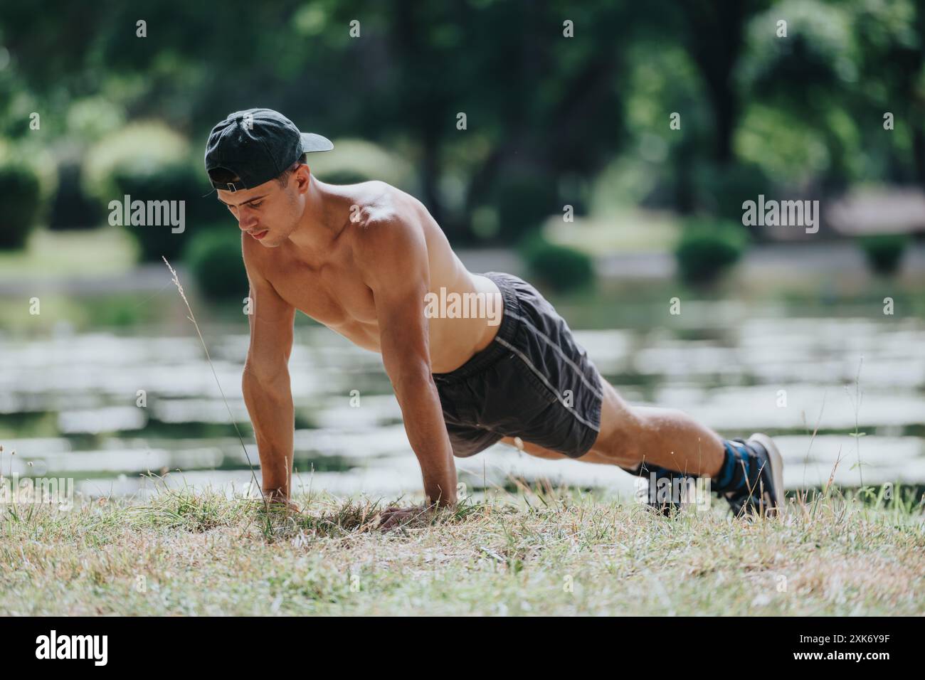 Young man doing push-ups in a park for outdoor fitness and exercise ...