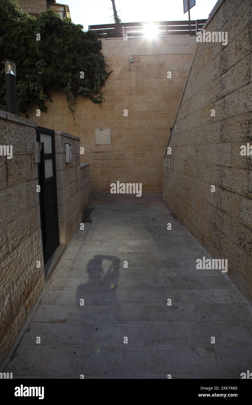 Weird, strange, man is between walls shooting the sun, his shadow seen ...