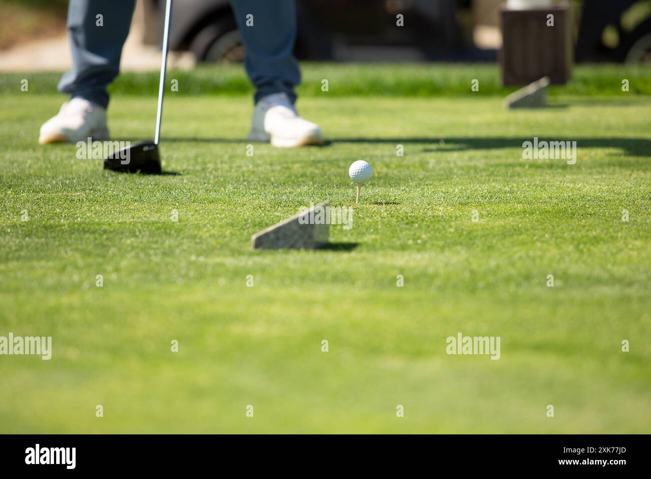 A view of a golfer preparing to swing his club at a golf ball resting ...