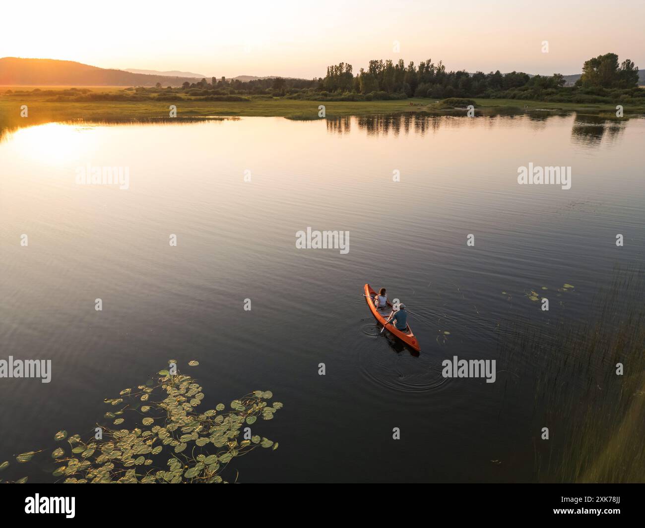 Couple paddling a canoe across a serene lake, enjoying a beautiful ...