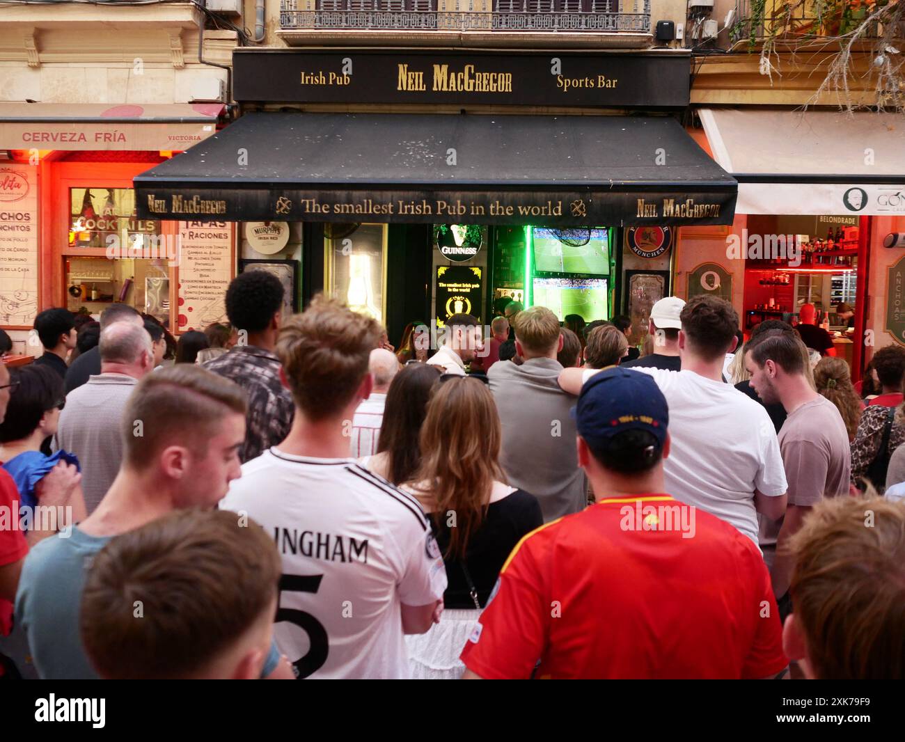 International football supporters on the street outside a bar follow a ...
