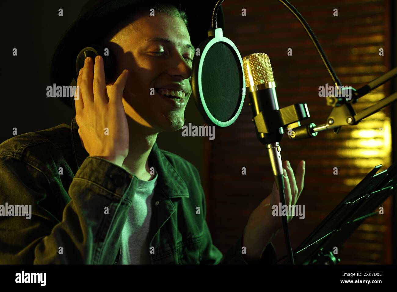 Vocalist with headphones singing into microphone in professional record ...