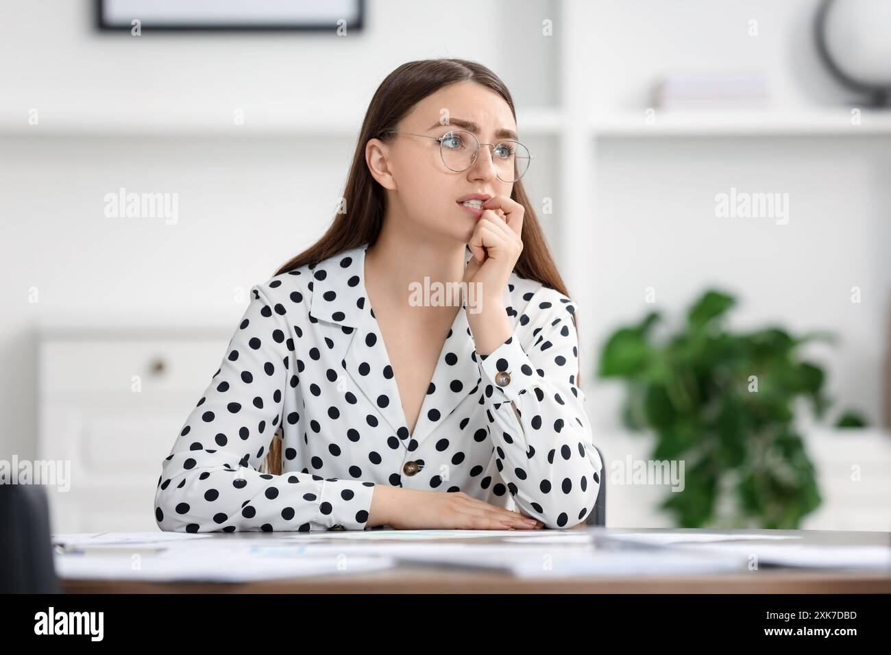 Embarrassed woman in glasses at table in office Stock Photo - Alamy