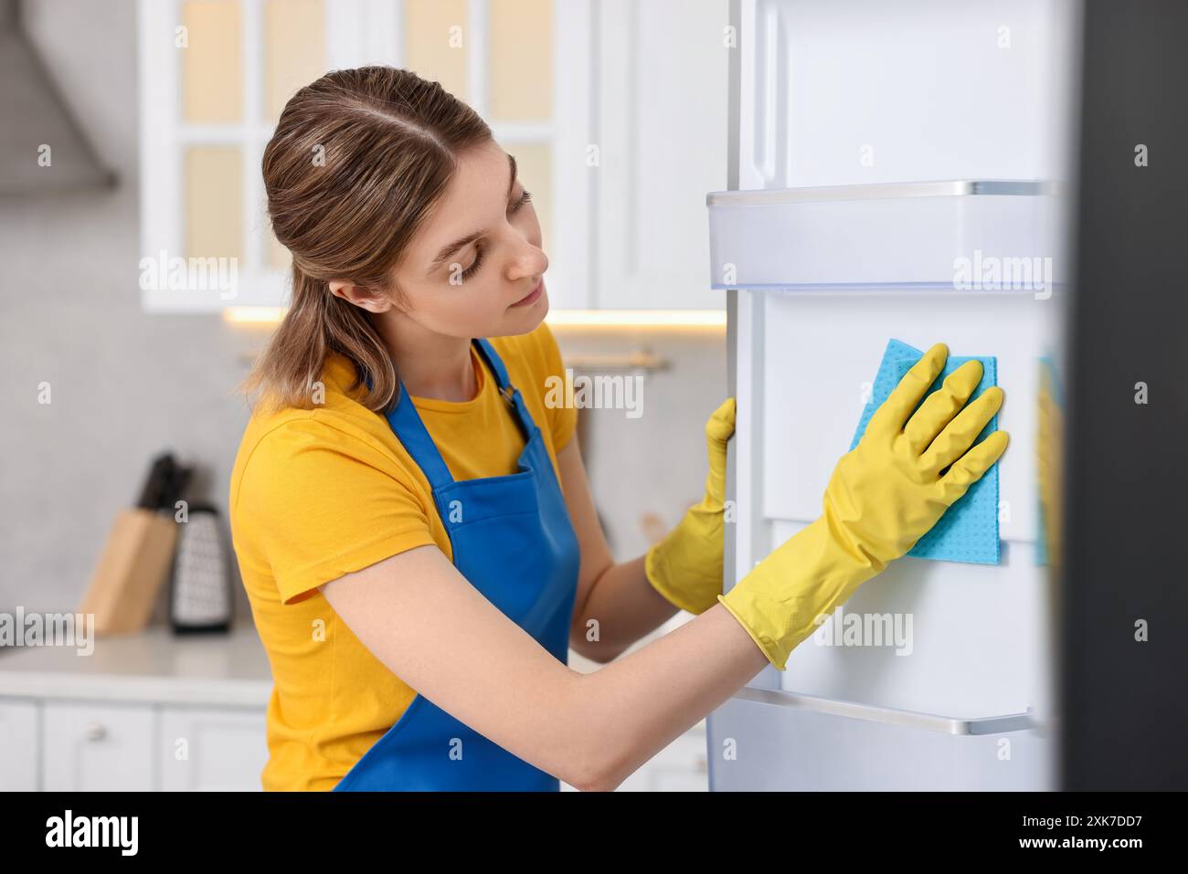 Professional janitor wearing uniform cleaning fridge in kitchen Stock ...