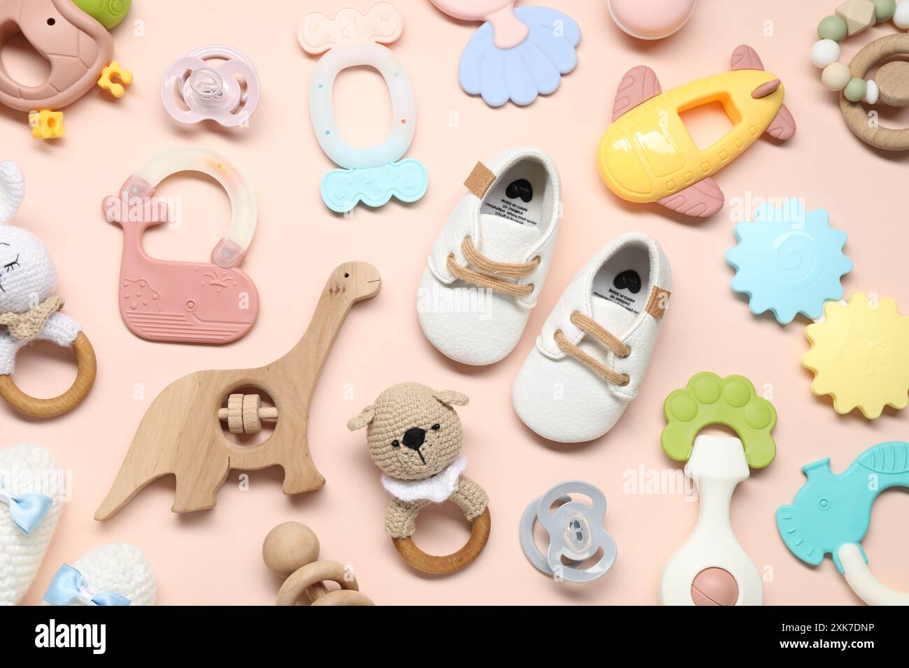Colorful rattles, baby shoes and pacifiers on beige background, flat ...