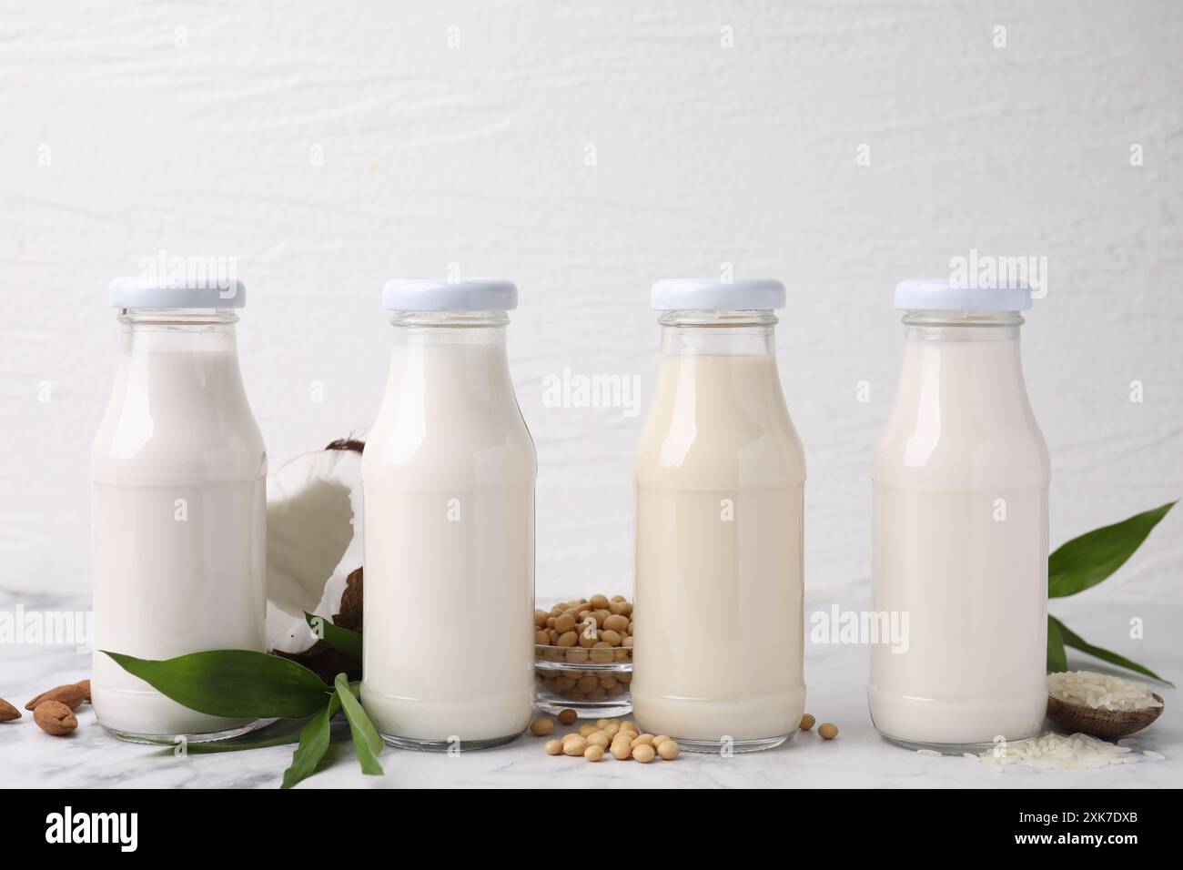 Different types of vegan milk in bottles with ingredients and green ...