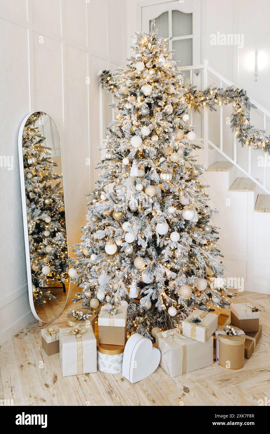 A large Christmas tree decorated with balls and garlands and boxes with ...