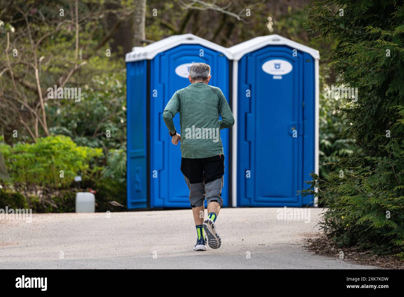 Old man running in front of two portable toilets Stock Photo - Alamy