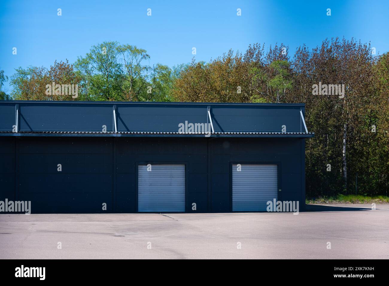 Grey warehouse with two garage ports Stock Photo - Alamy