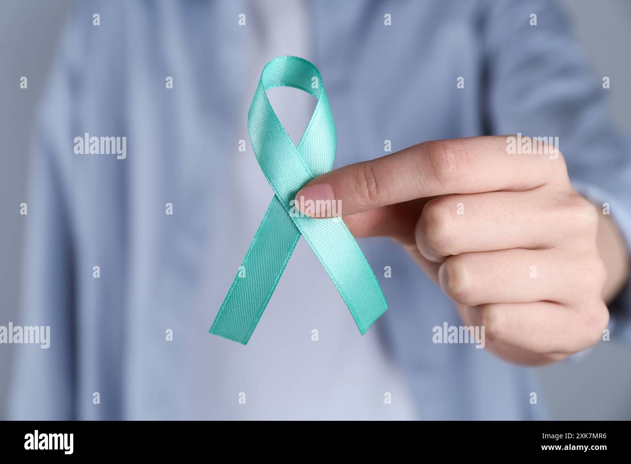Woman holding turquoise awareness ribbon, closeup view Stock Photo - Alamy