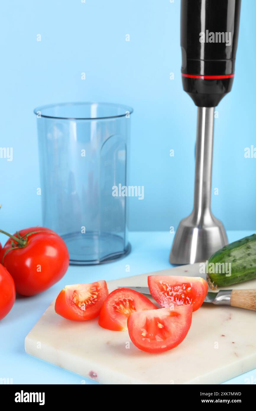 Hand blender kit, fresh vegetables and knife on light blue background ...