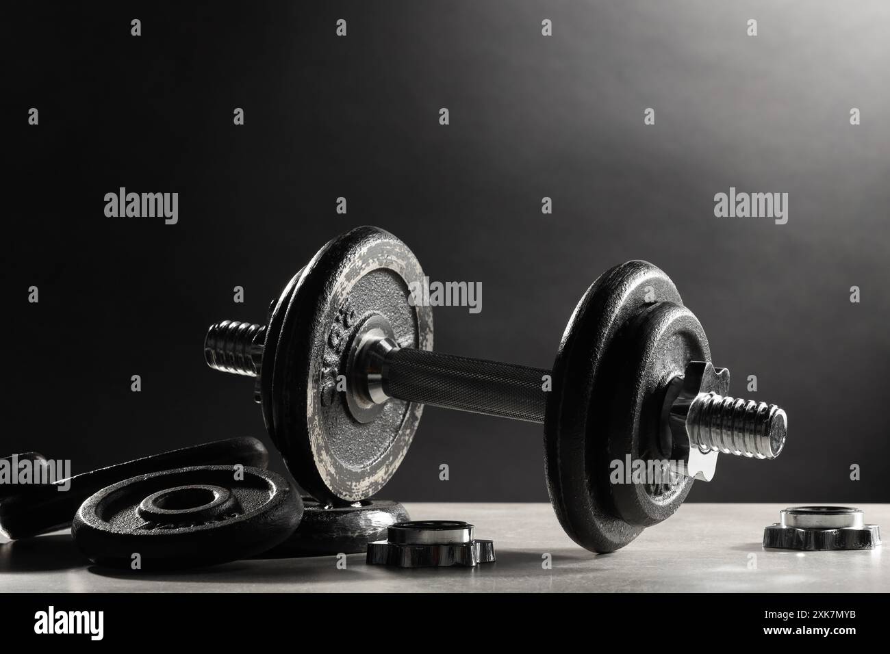Barbell and parts of one on light table against dark background Stock ...
