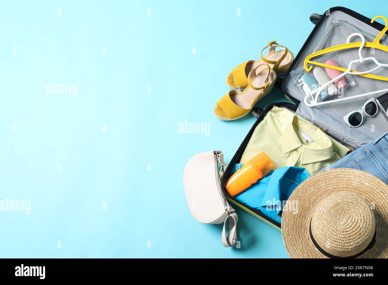 Open suitcase with traveler's belongings on light blue background, flat ...