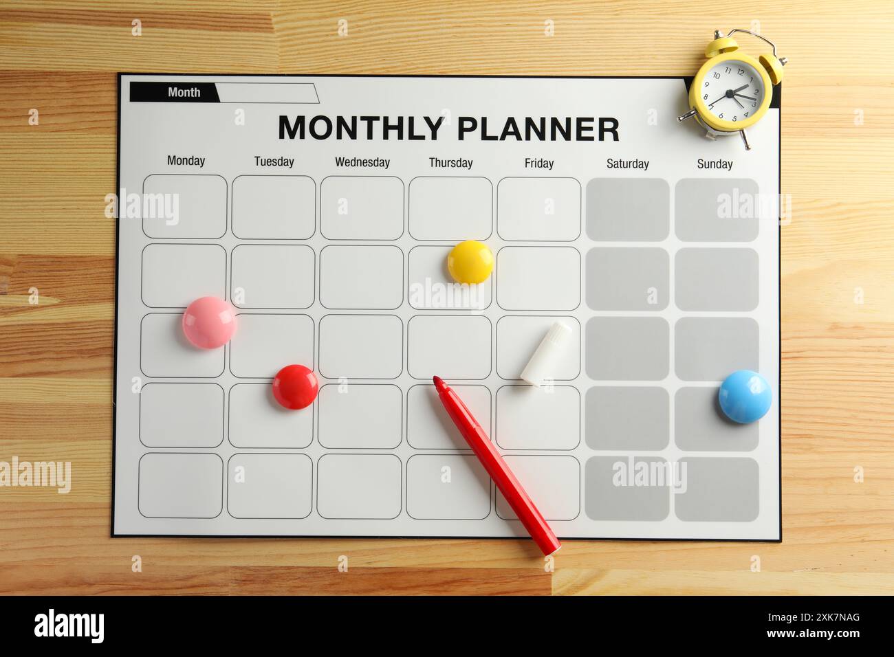 Timetable. Monthly planner, felt pen, drawing pins and alarm clock on ...