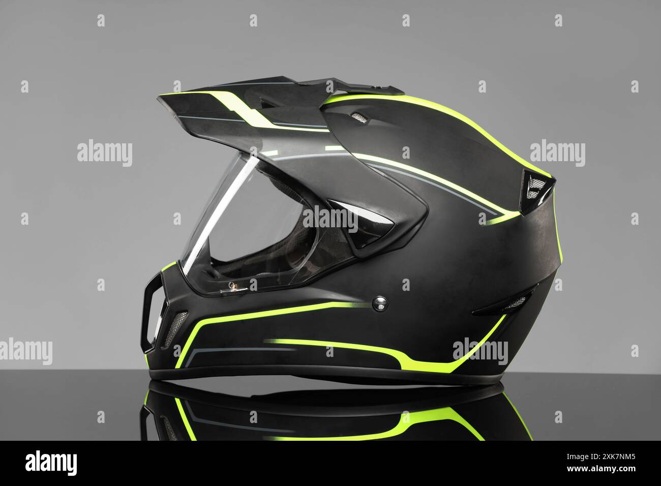 Modern motorcycle helmet with visor on mirror surface against light ...