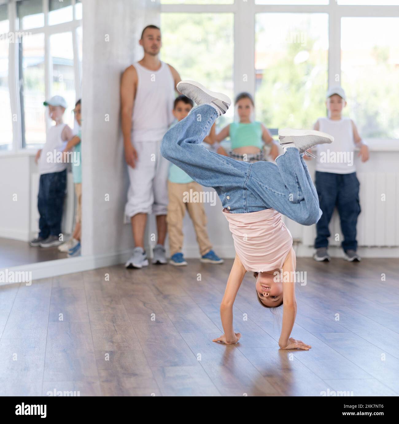 Group of happy sporty kids with male teacher training hip hop in dance ...