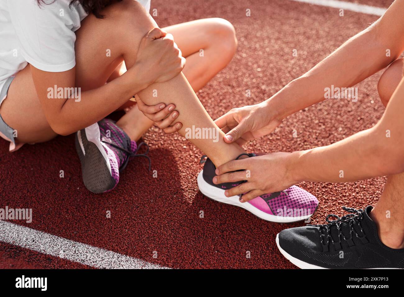 Sports injury. Man helping woman with leg pain at stadium, closeup ...