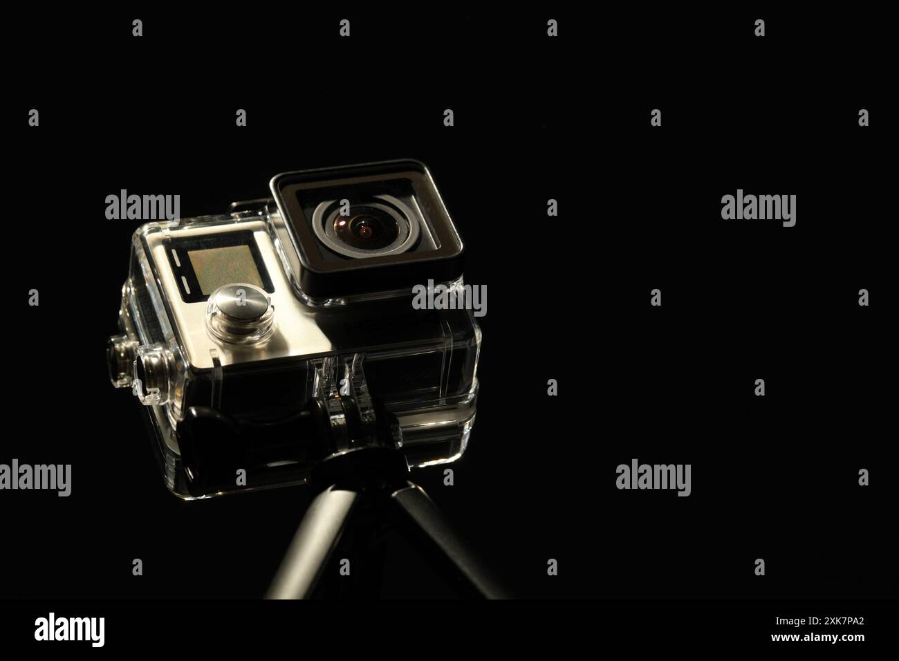Modern action camera and tripod against black background, closeup ...