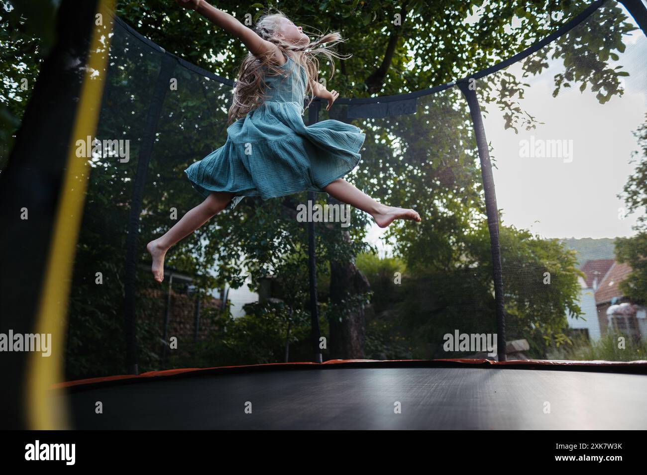 Little girl jumping on trampoline in the backyard. Dangers and risks of ...