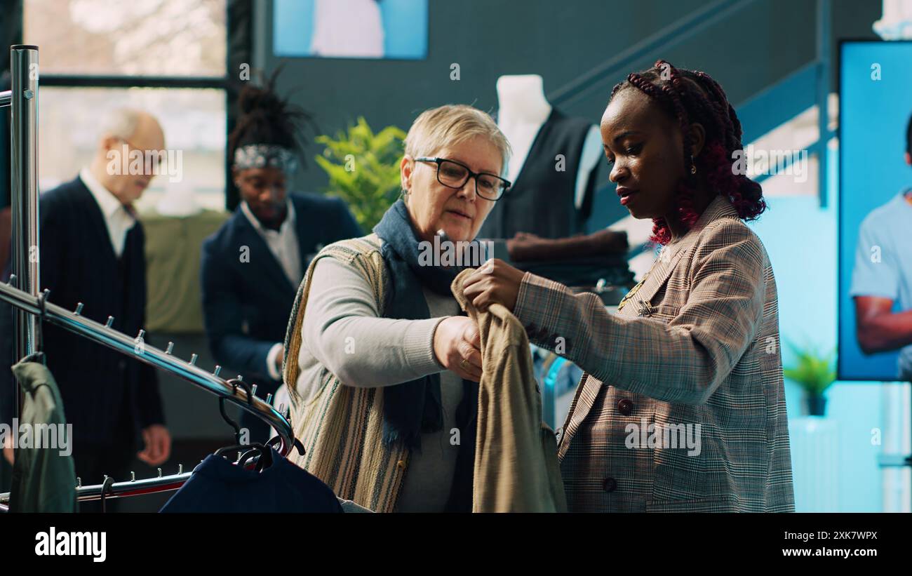 African american retail clerk showing new fashion collection to senior ...