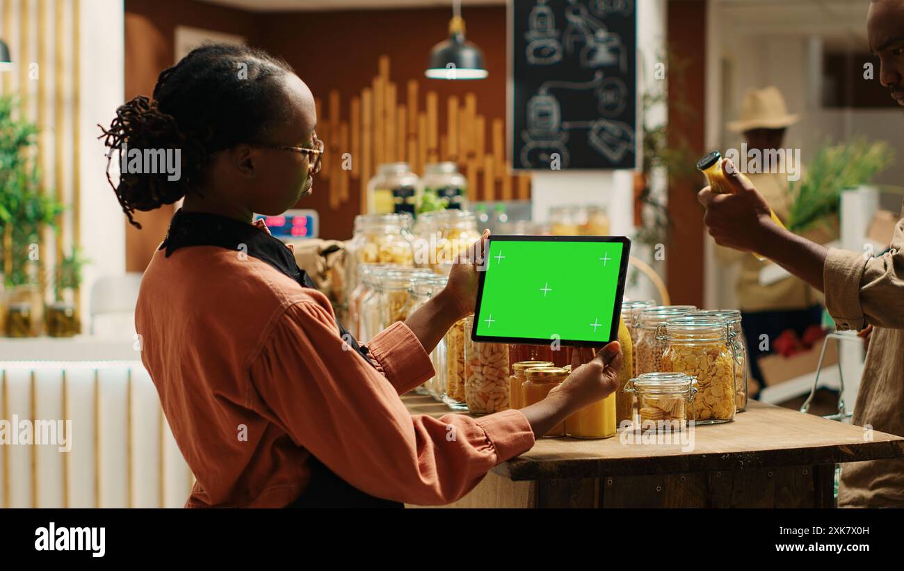 African american woman uses greenscreen on tablet in supermarket ...