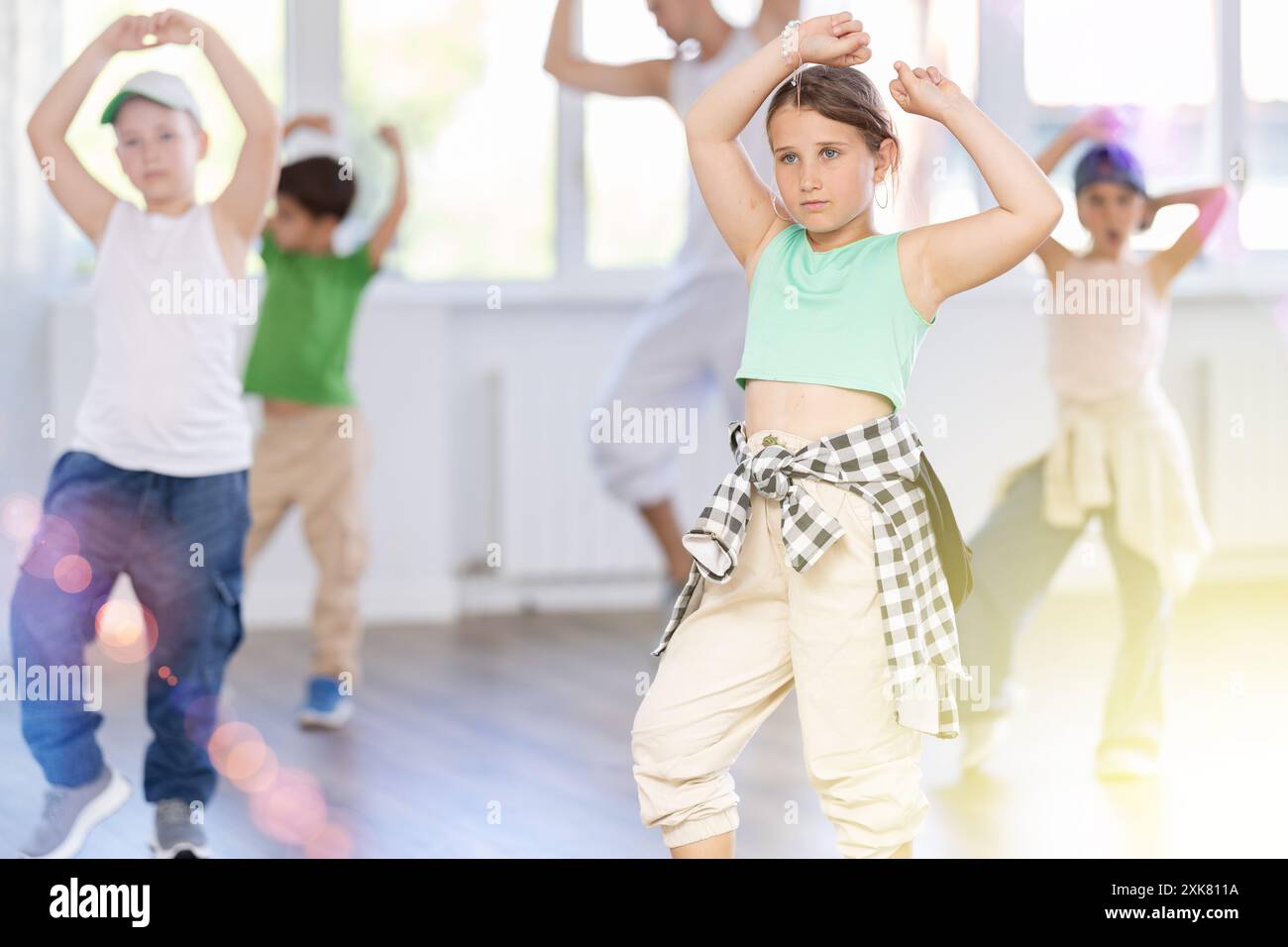Portrait of confident tween girl hip hop dancer training during group ...