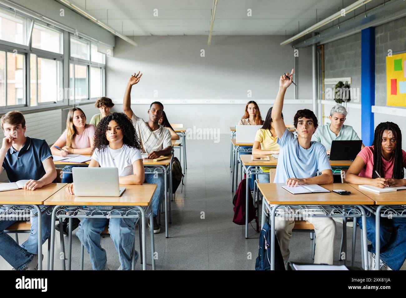 Young students raising hand to ask a question at high school classroom ...