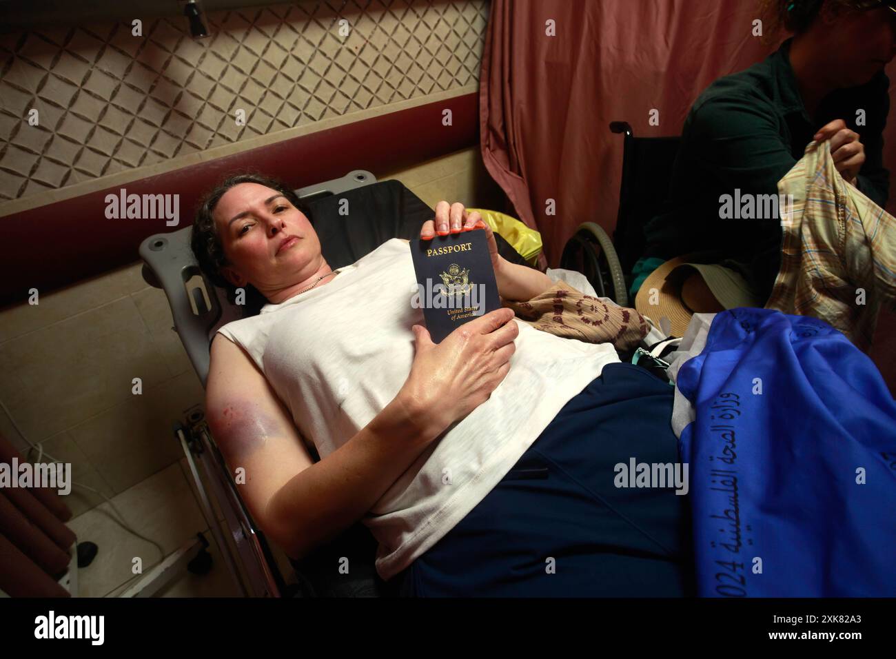 A foreign volunteer sits on the bed and shows her passport while ...