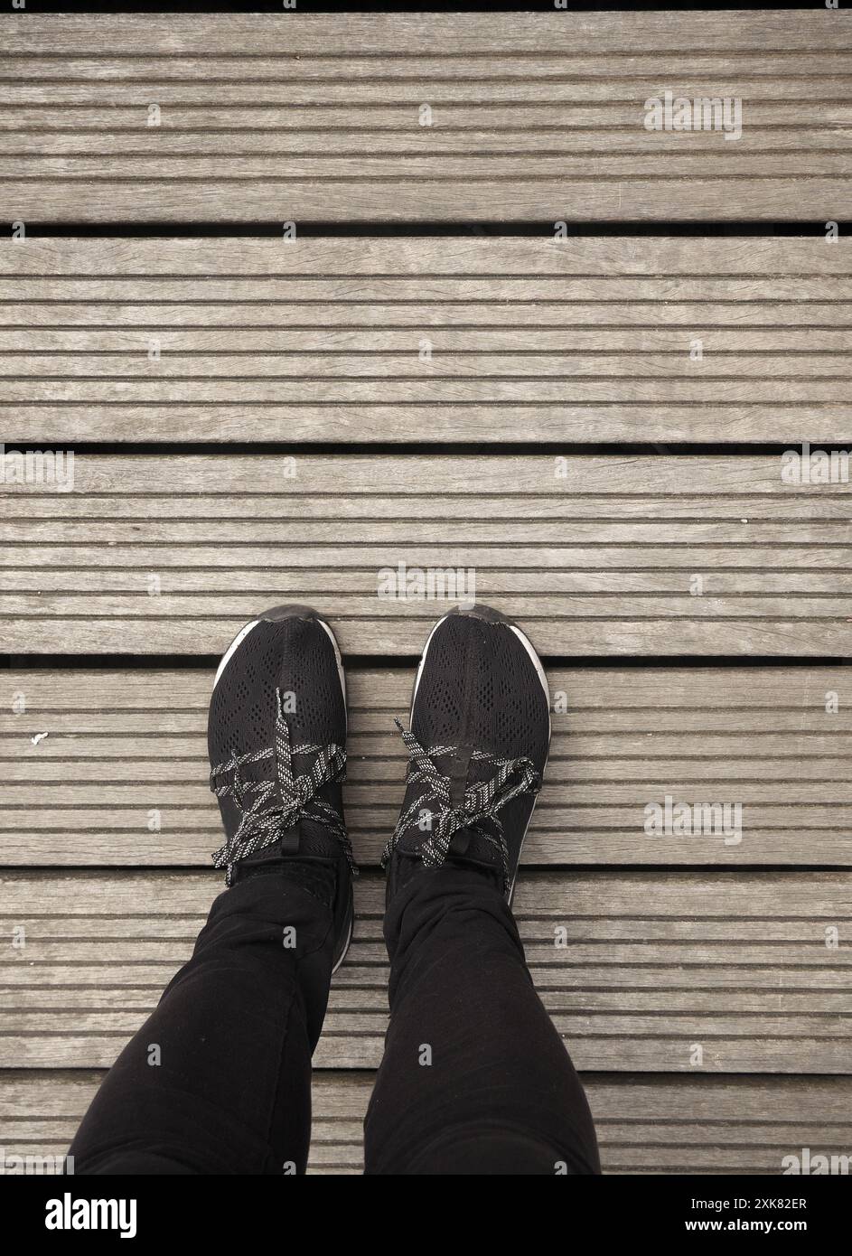 A top view of male legs in stylish shoes standing on wooden background ...