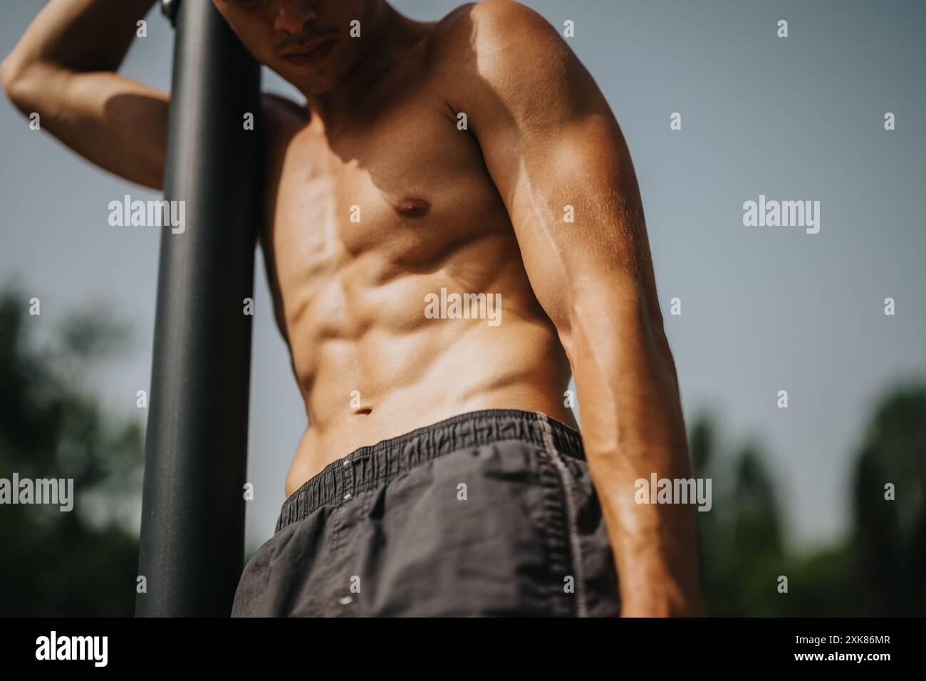 Athletic young man showing defined abs and muscular physique outdoors ...
